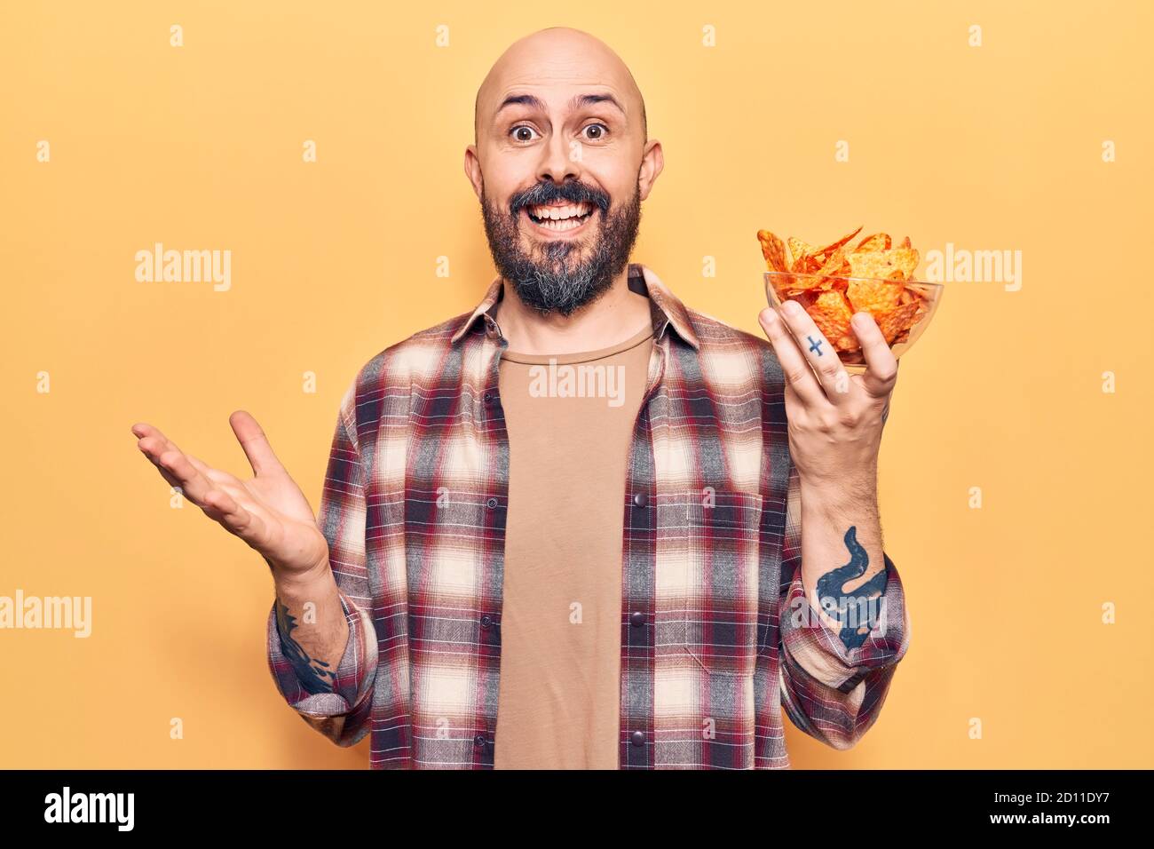 Young handsome man holding nachos potato chips celebrating achievement ...