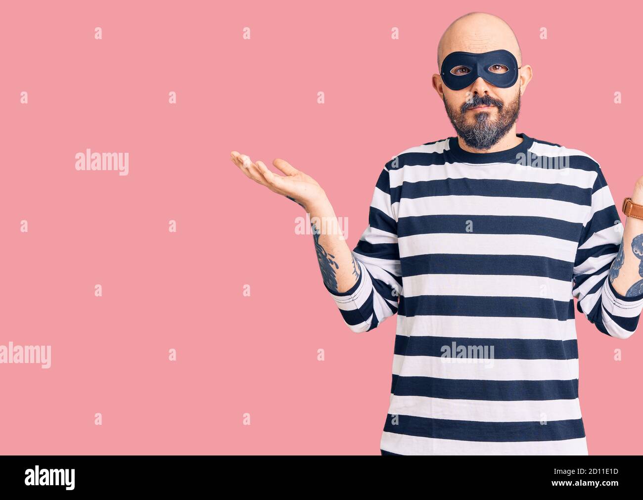 Young handsome man wearing burglar mask clueless and confused ...