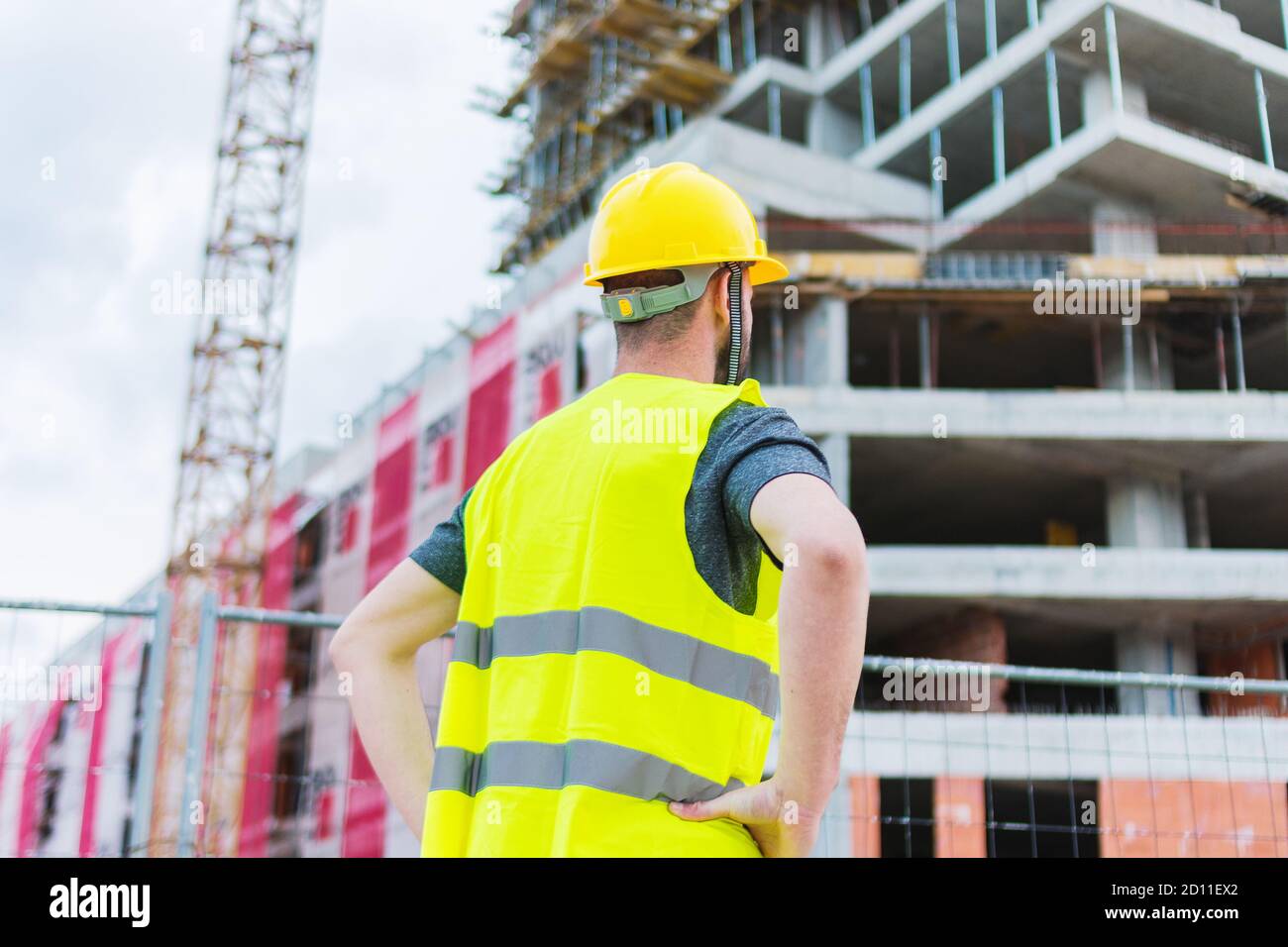 An engineer posing in front of building construction he is working of ...