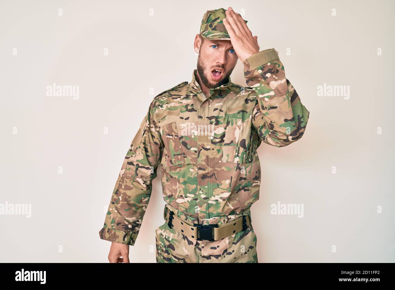 Young caucasian man wearing camouflage army uniform surprised with hand ...