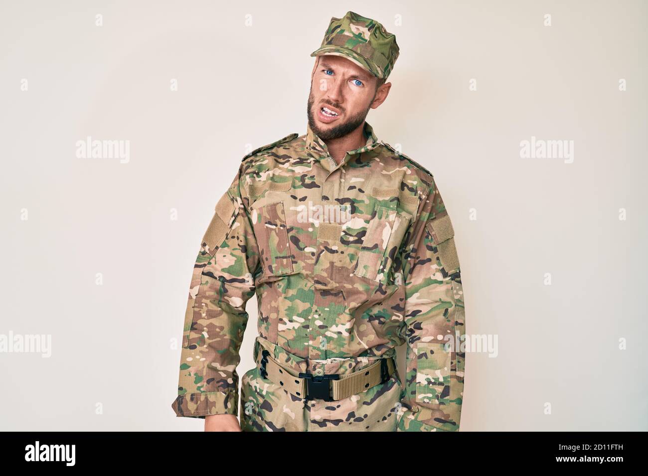 Young caucasian man wearing camouflage army uniform in shock face ...