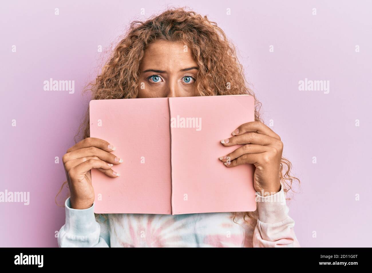 Beautiful caucasian teenager girl reading a book covering face in shock ...