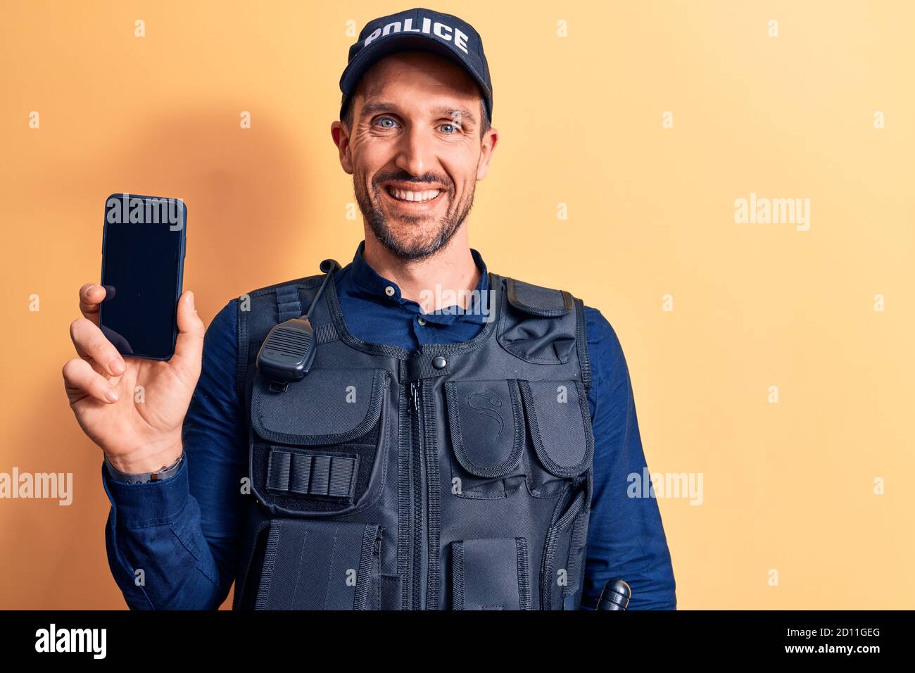 Handsome policeman wearing uniform and bulletprof holding smartphone ...