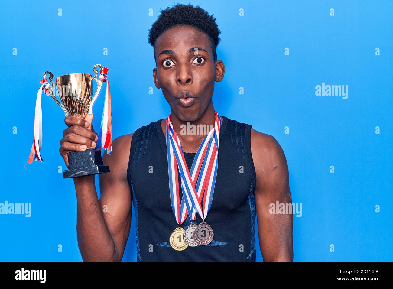 Young african american man holding champion trophy wearing medals ...