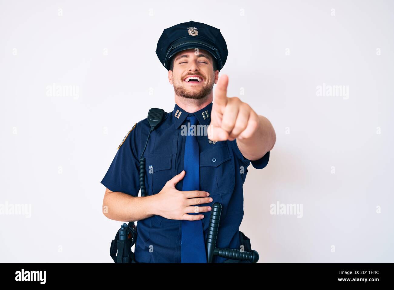 Young caucasian man wearing police uniform laughing at you, pointing ...