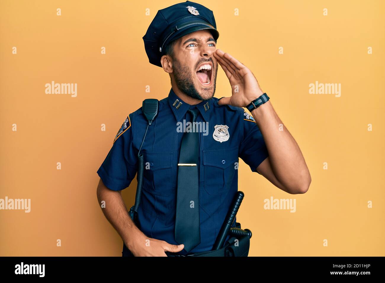 Handsome hispanic man wearing police uniform shouting and screaming ...