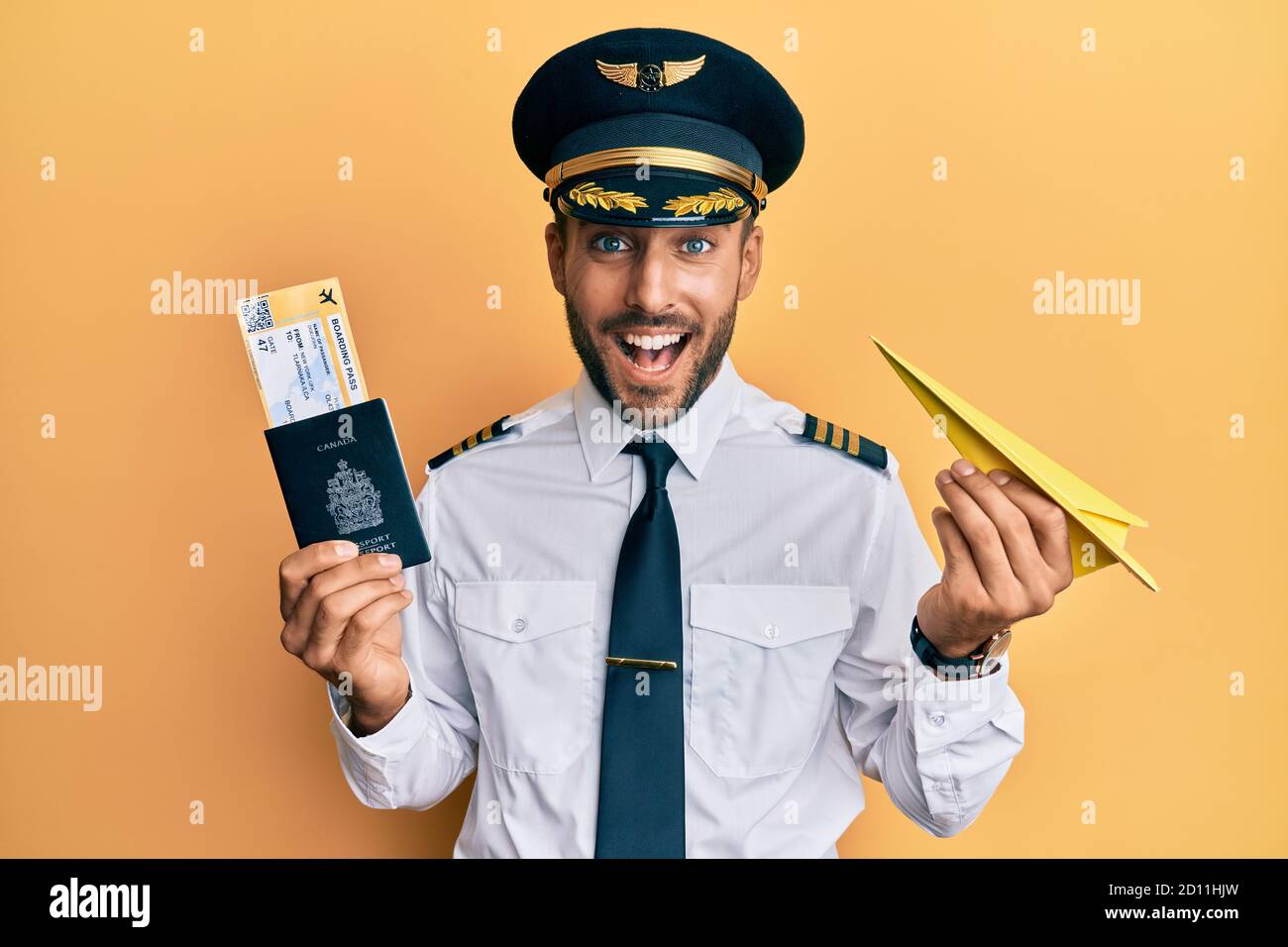 Handsome hispanic pilot man holding paper plane and passport smiling ...