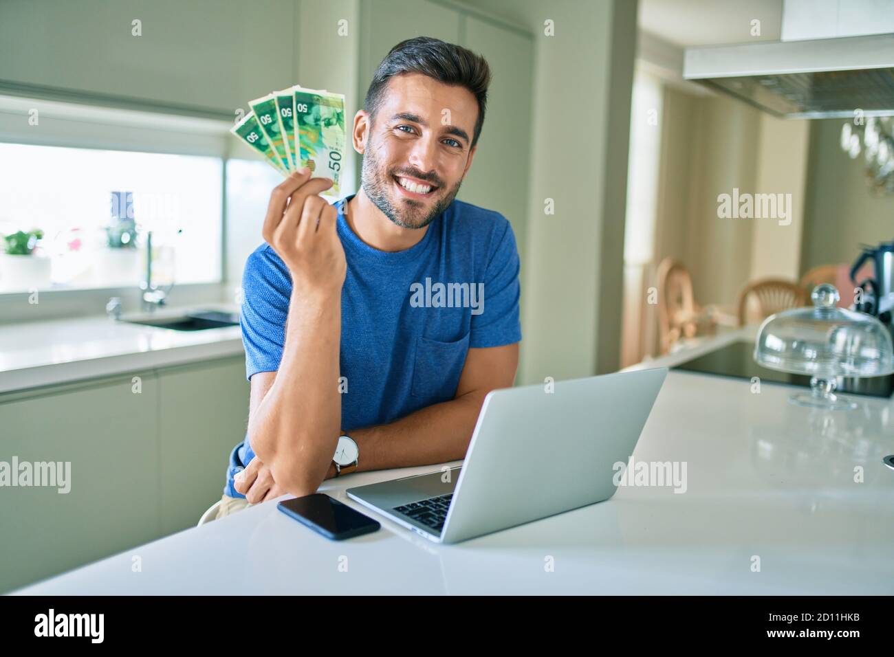 Young handsome man smiling happy holding israeli shekels banknotes at ...