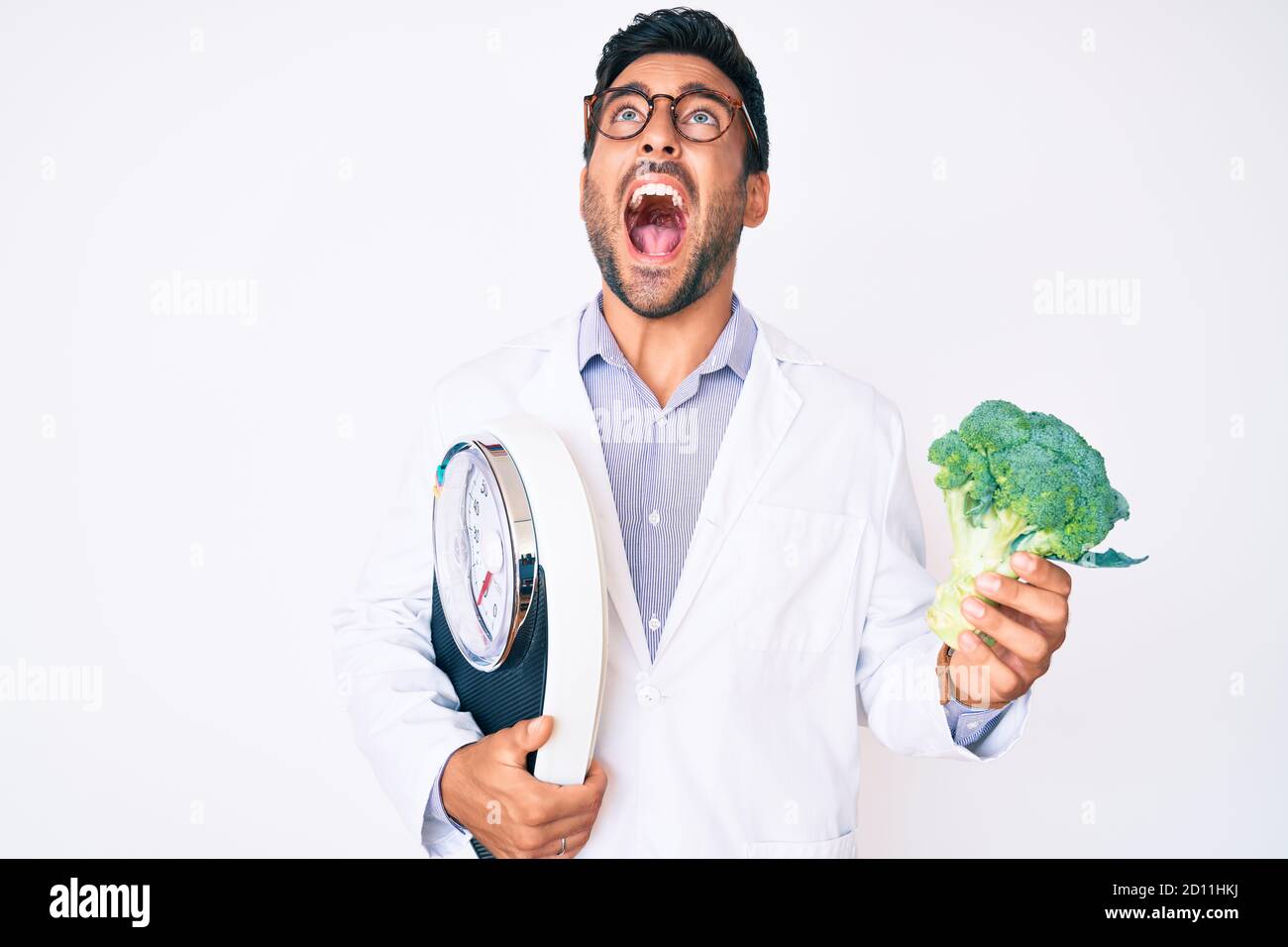 Young hispanic man as nutritionist doctor holding weighing machine and ...