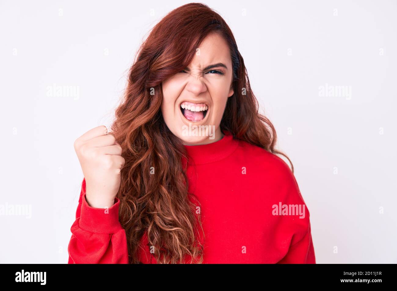 Young beautiful woman wearing casual clothes angry and mad raising fist ...