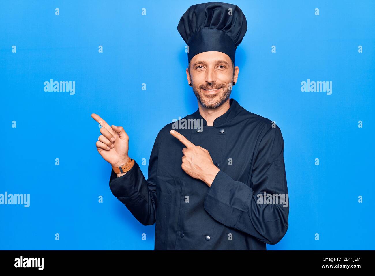 Young handsome man wearing cooker uniform smiling and looking at the ...