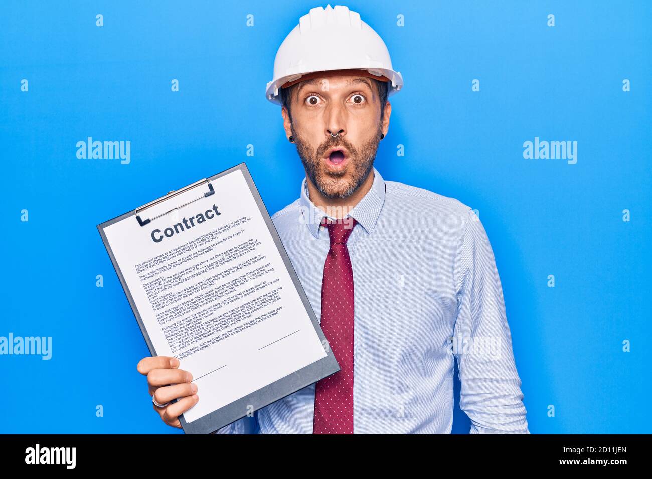 Young handsome man wearing architect hardhat holding contract document ...