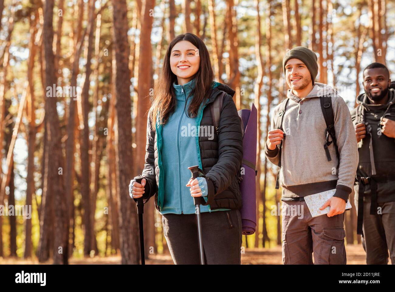 Smiling hikers looking at camera over pine forest background Stock ...