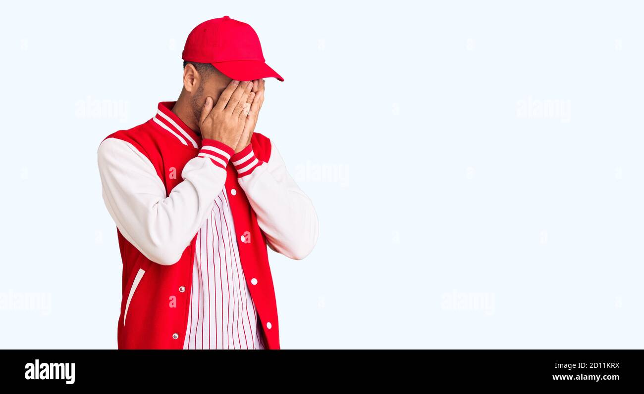 Young hispanic man wearing baseball uniform with sad expression ...