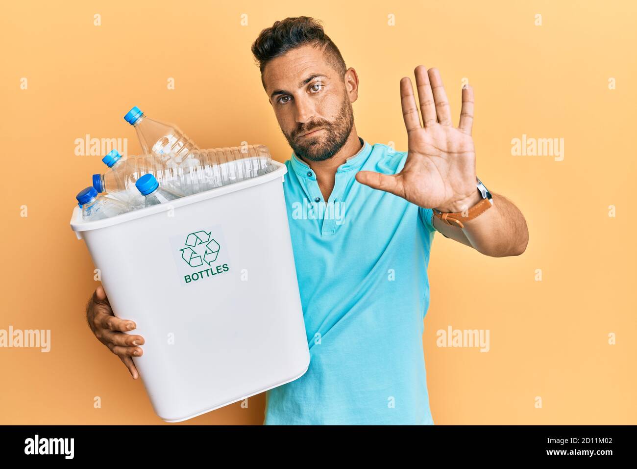 Handsome man with beard holding recycling wastebasket with plastic ...