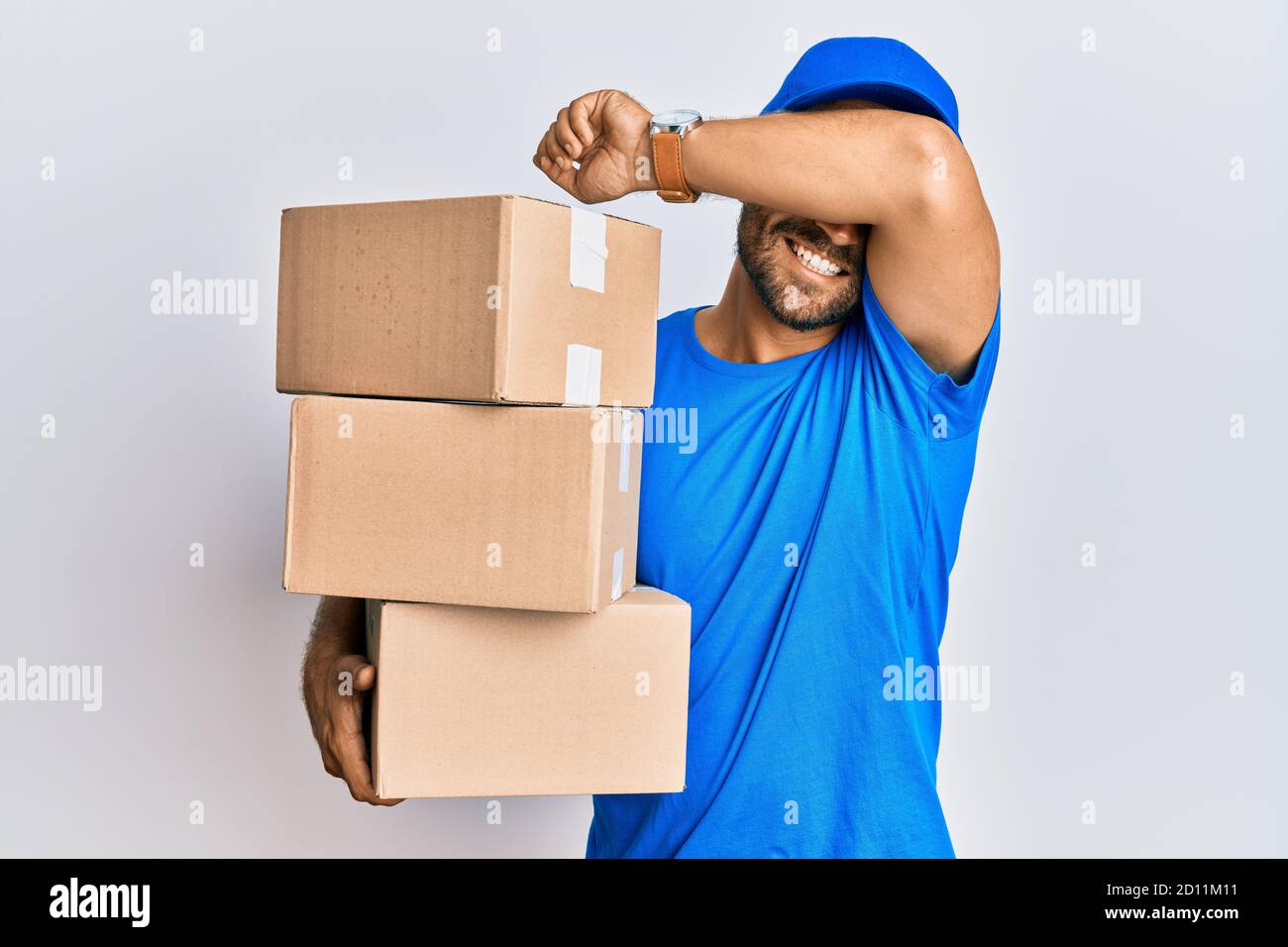 Handsome man with beard wearing courier uniform holding delivery ...