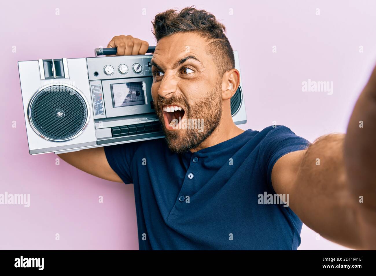 Handsome man with beard holding boombox, listening to music angry and ...