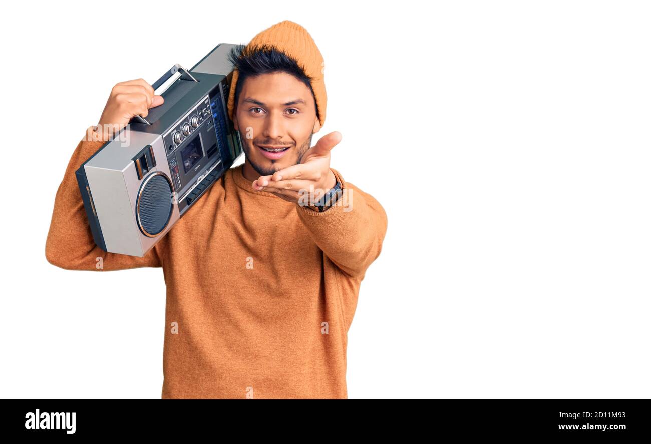 Handsome latin american young man holding boombox, listening to music ...