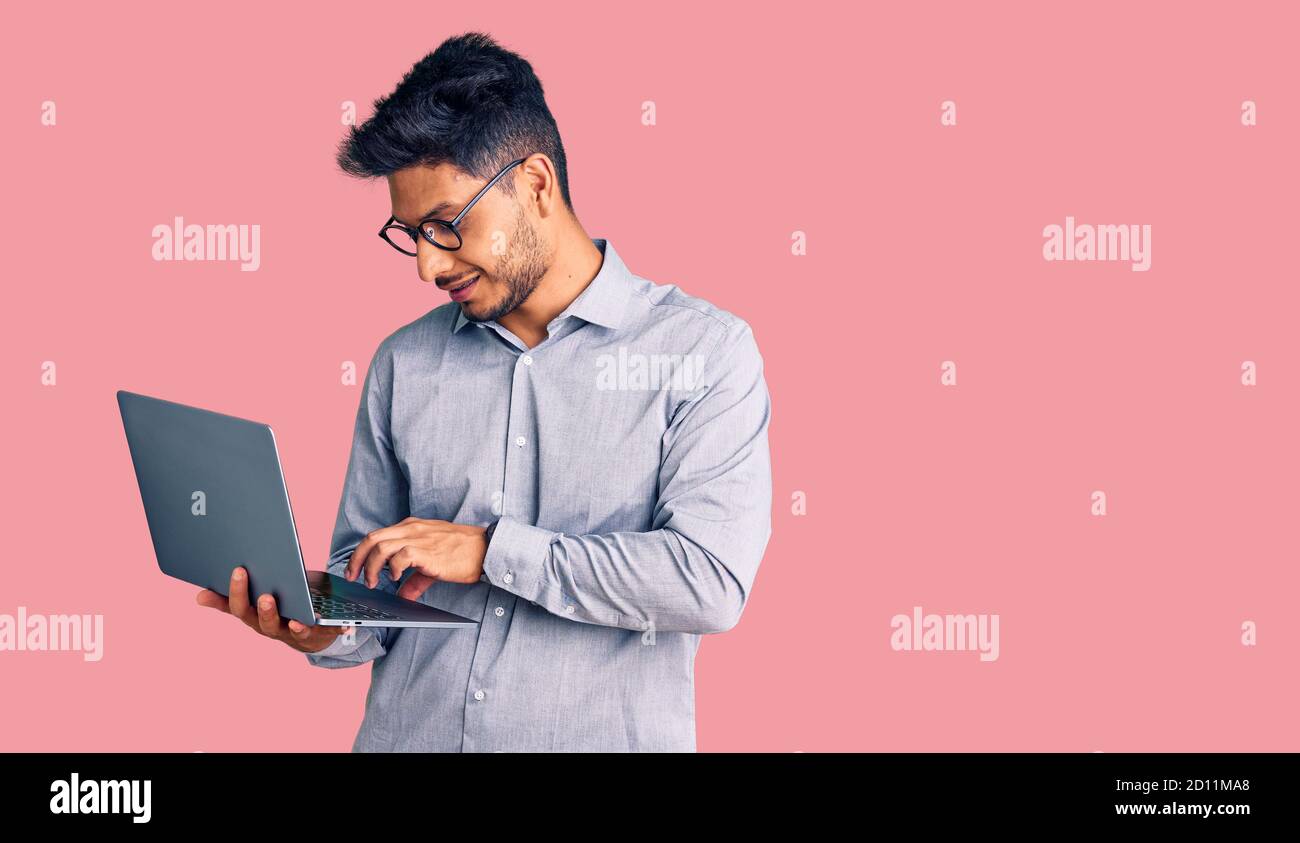 Handsome latin american young man working using computer laptop looking ...