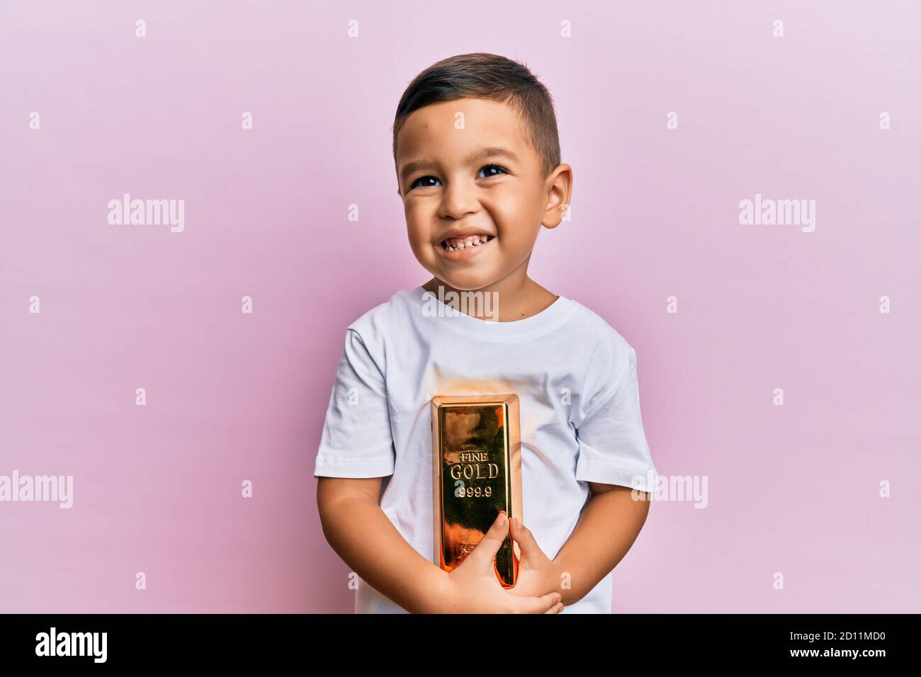 Adorable latin toddler holding gold ingot looking positive and happy ...