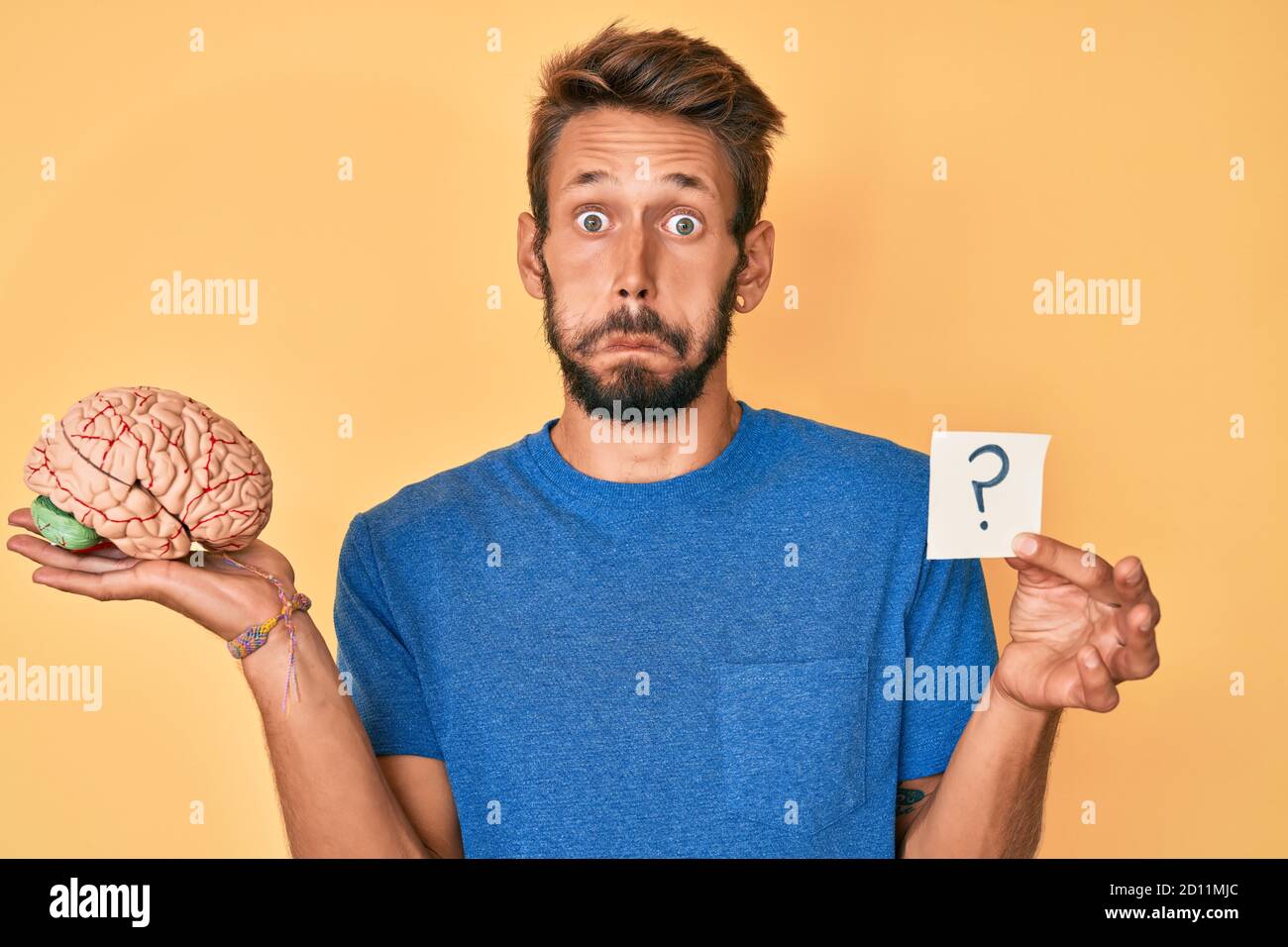 Handsome caucasian man with beard holding brain and question mark ...