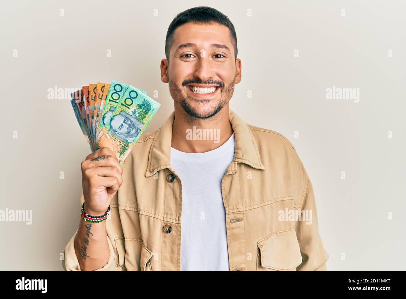 Handsome man with tattoos holding australian dollars looking positive ...