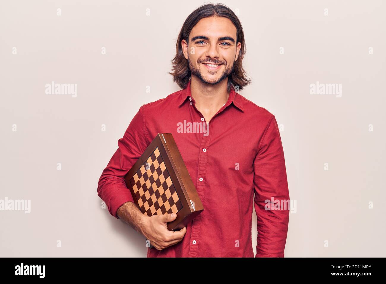 Young handsome man holding chess looking positive and happy standing ...