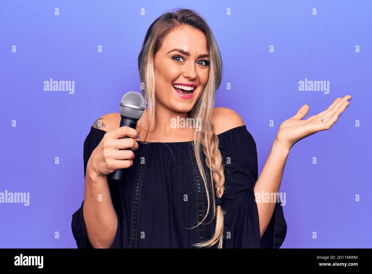 Young beautiful blonde singer woman singing using microphone over ...