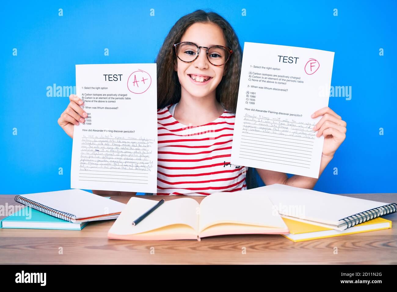 Cute hispanic girl showing failed and passe exam sitting on the table ...