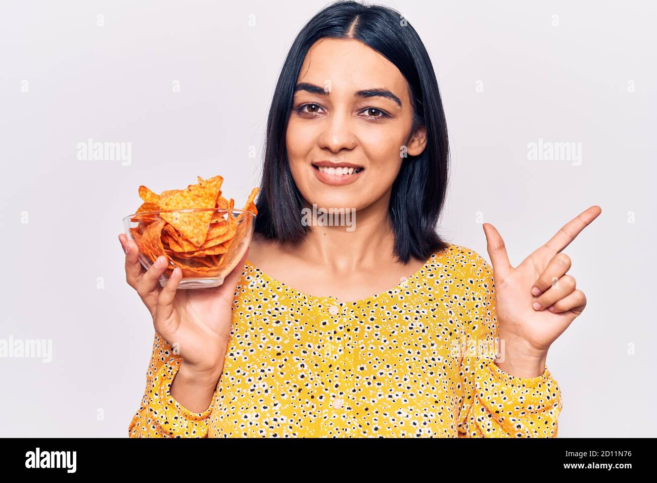 Young beautiful latin woman holding nachos potato chips smiling happy ...