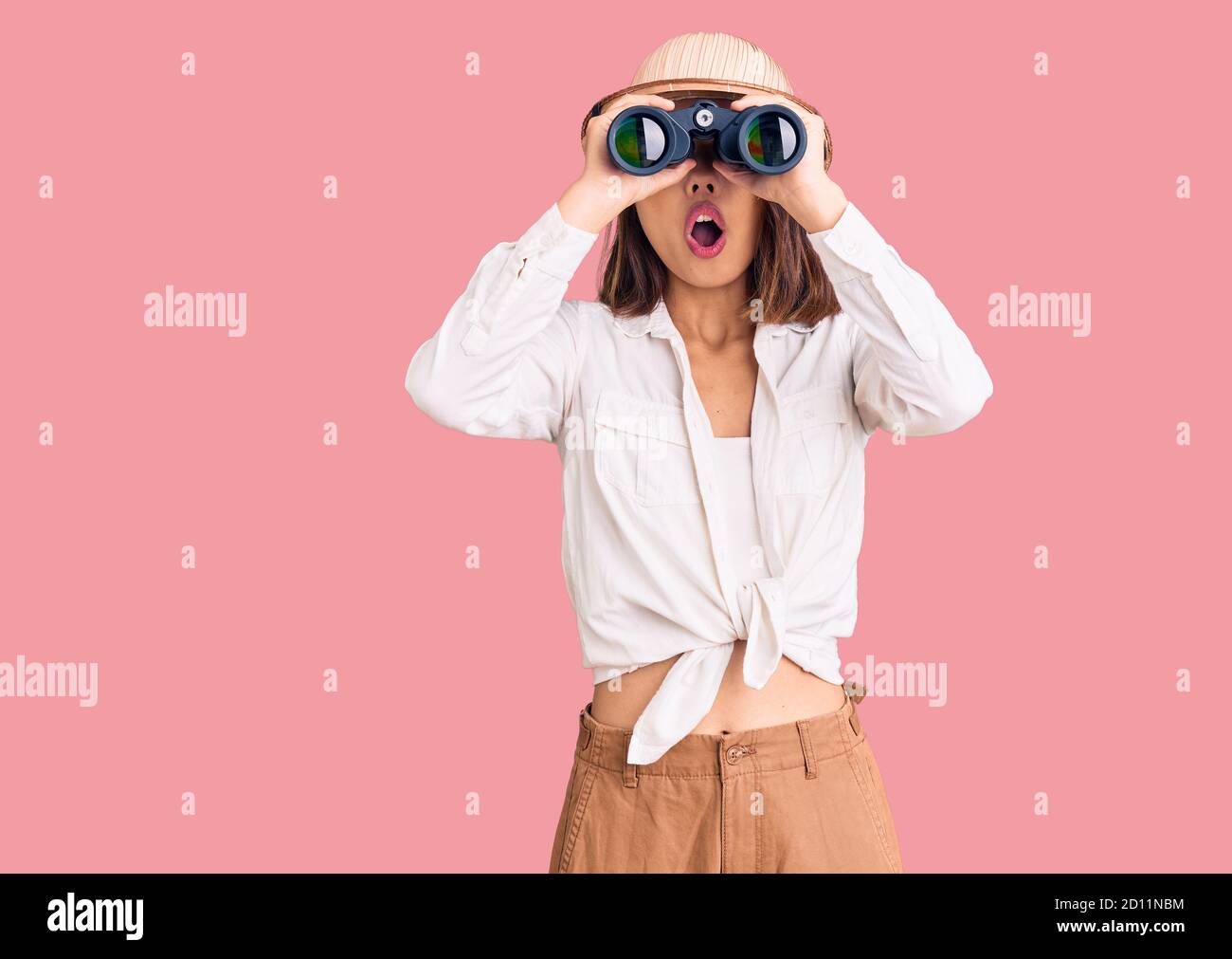 Young beautiful chinese girl wearing explorer hat holding binoculars ...