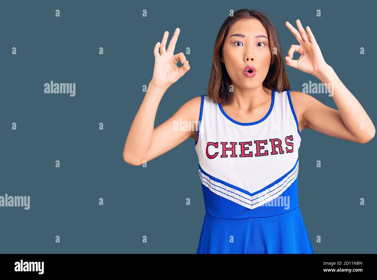 Young beautiful chinese girl wearing cheerleader uniform looking ...