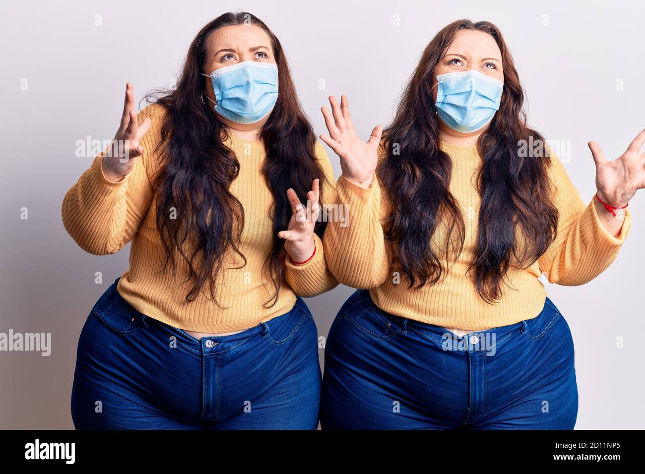 Young plus size twins wearing medical mask crazy and mad shouting and ...