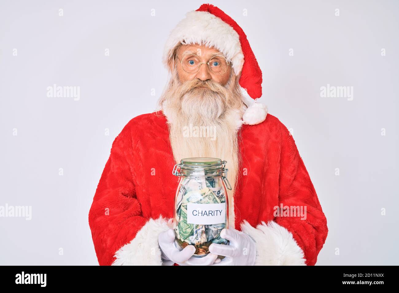 Old senior man wearing santa claus costume holding charity jar thinking ...