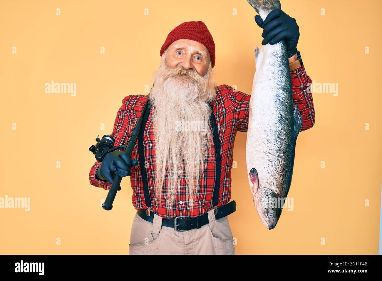 Old senior man with grey hair and long beard holding fishing rod and ...