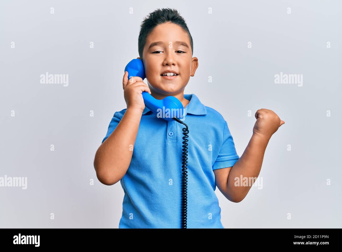 Little boy hispanic kid talking through vintage telephone screaming ...