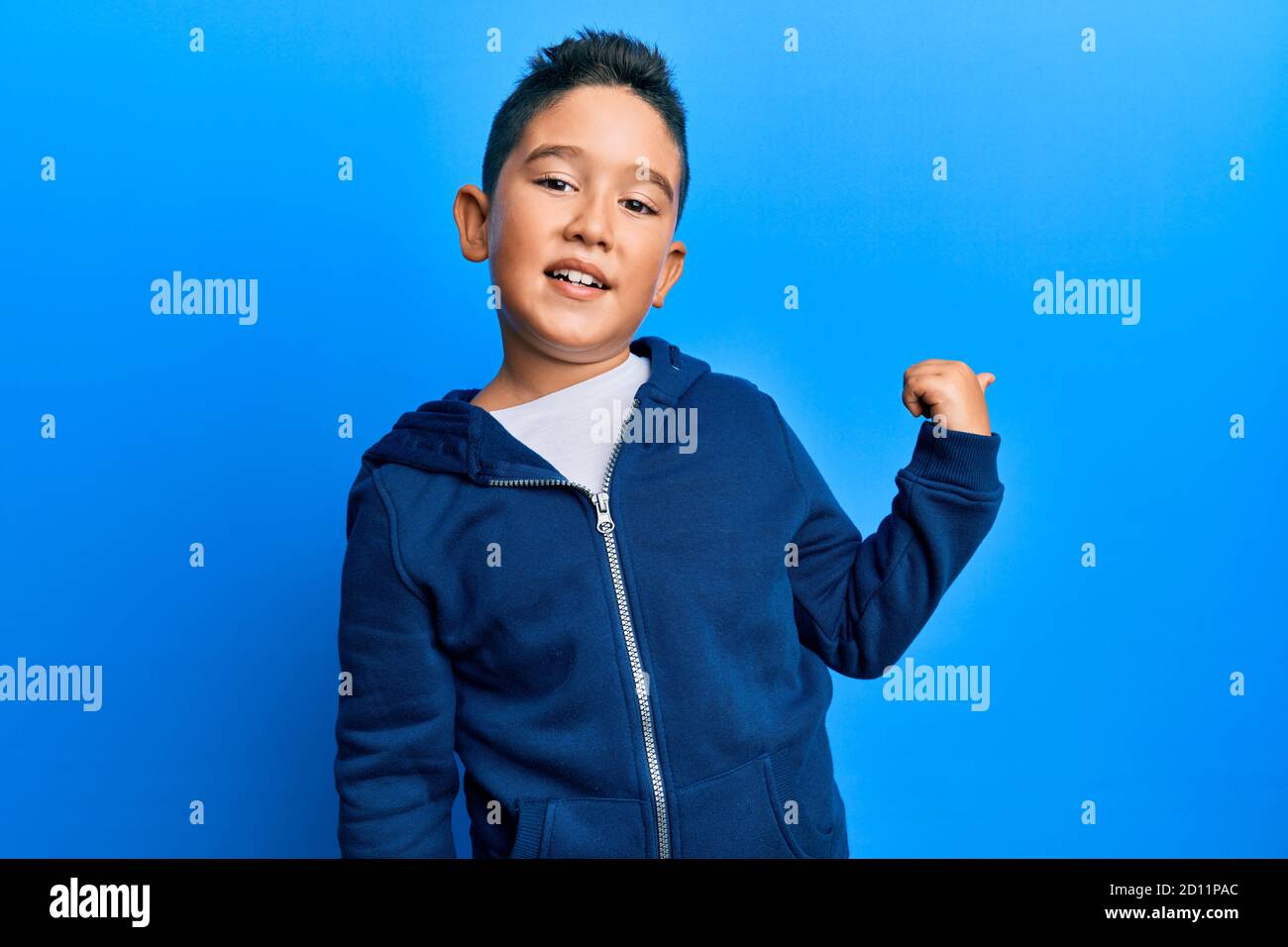Little boy hispanic kid wearing casual sporty jacket pointing thumb up ...