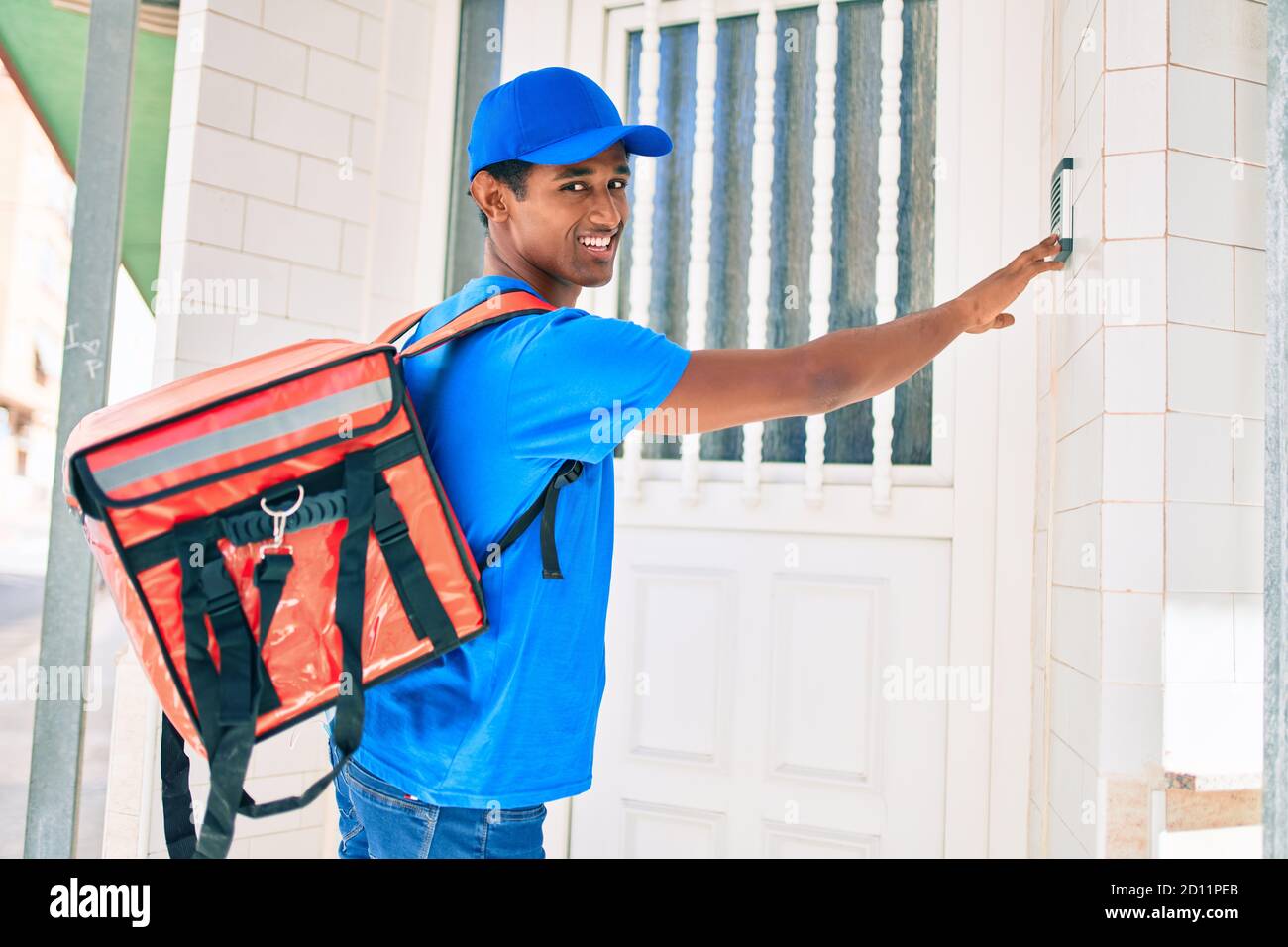 African delivery man wearing courier uniform outdoors knocking on the ...