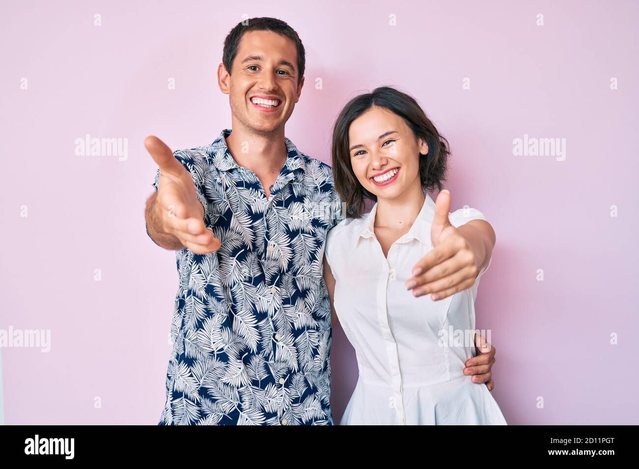 Beautiful couple wearing casual clothes smiling friendly offering ...