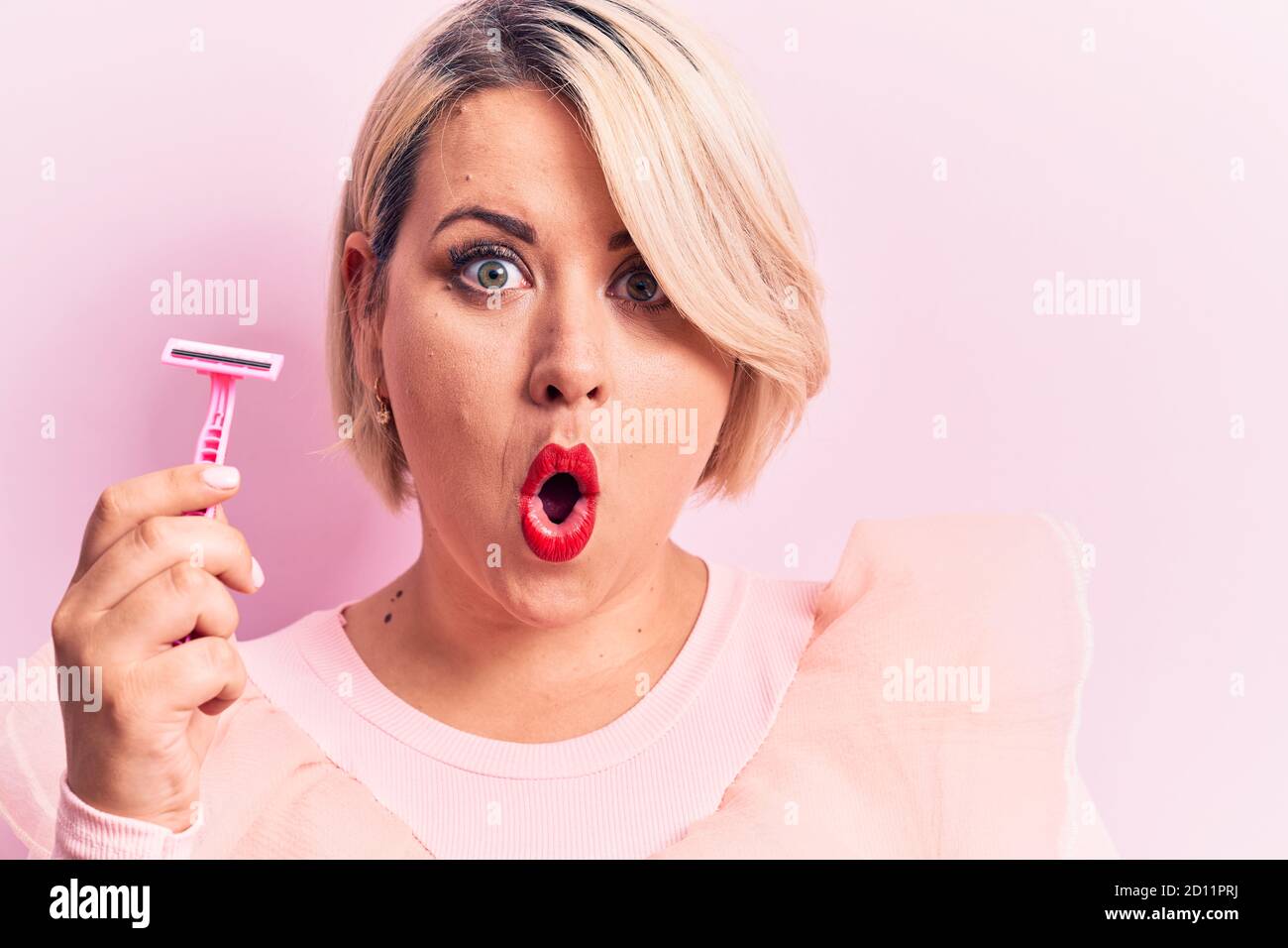 Young beautiful blonde plus size woman holding depilation razor over ...