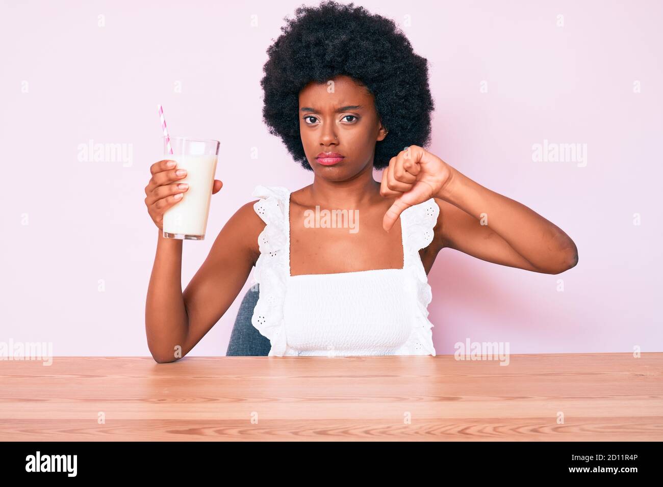 Young african american woman holding glass of milk with angry face ...