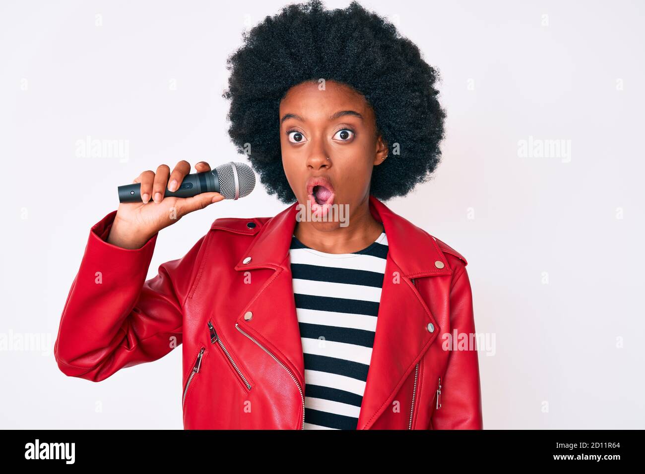 Young african american woman singing song using microphone scared and ...