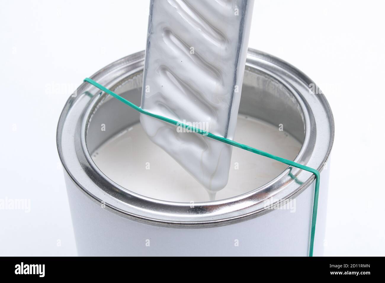 A man removes excess paint from a brush in a can on a white background ...