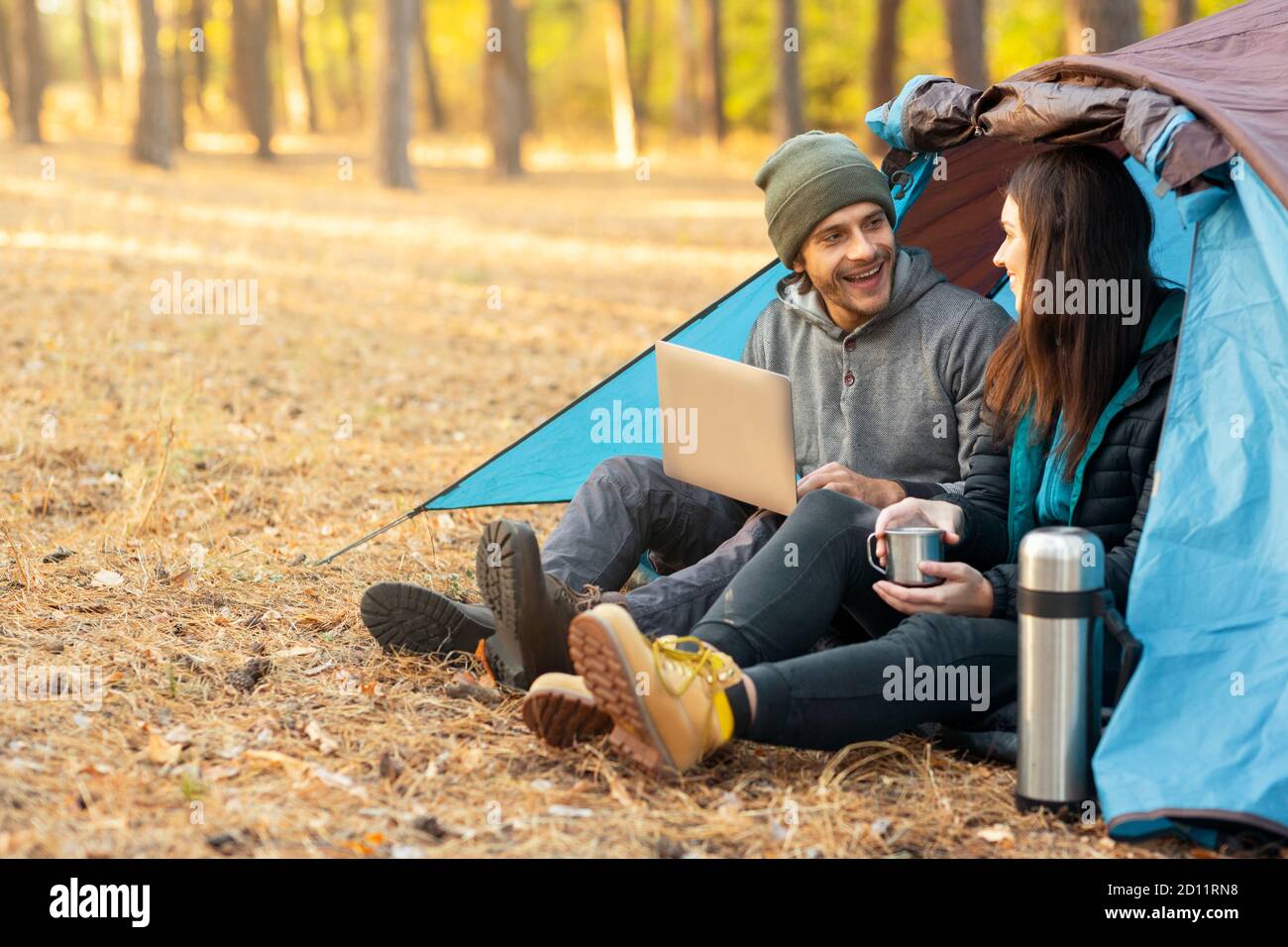 Romantic couple camping outdoors, sitting in tent with laptop Stock ...
