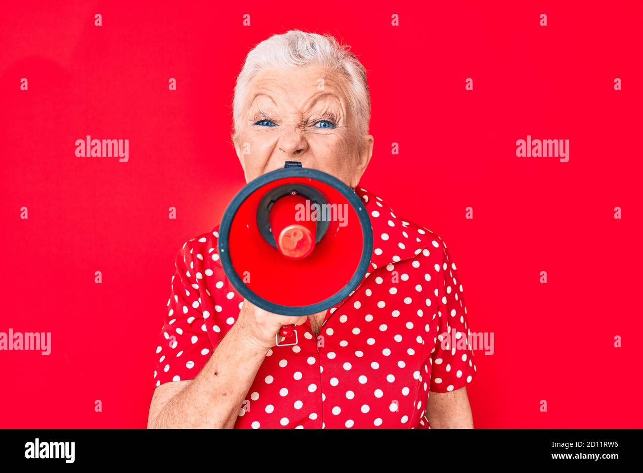 Senior beautiful grey-haired woman screaming using megaphone over ...