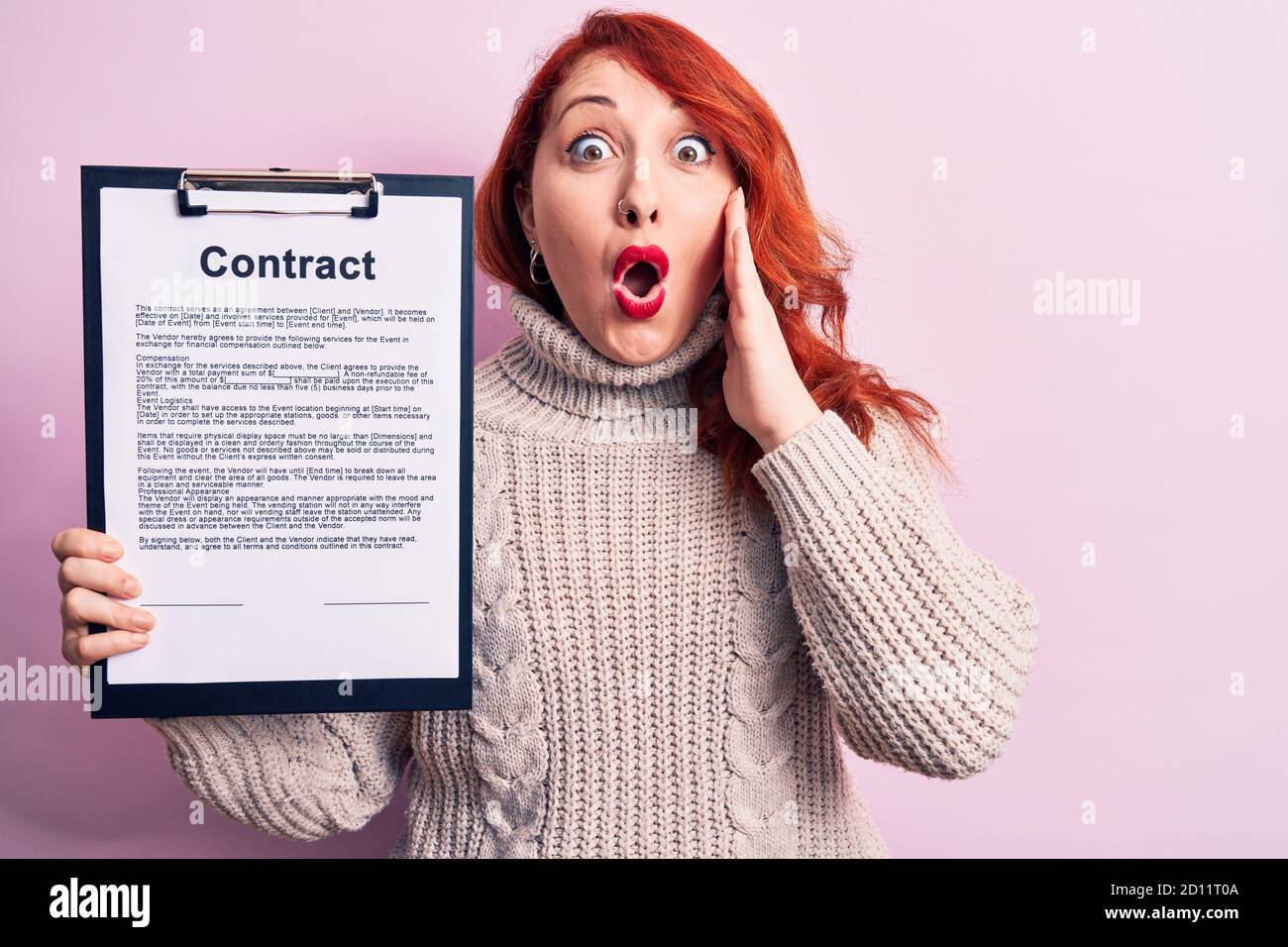Young redhead woman holding clipboard with contract document paper over ...