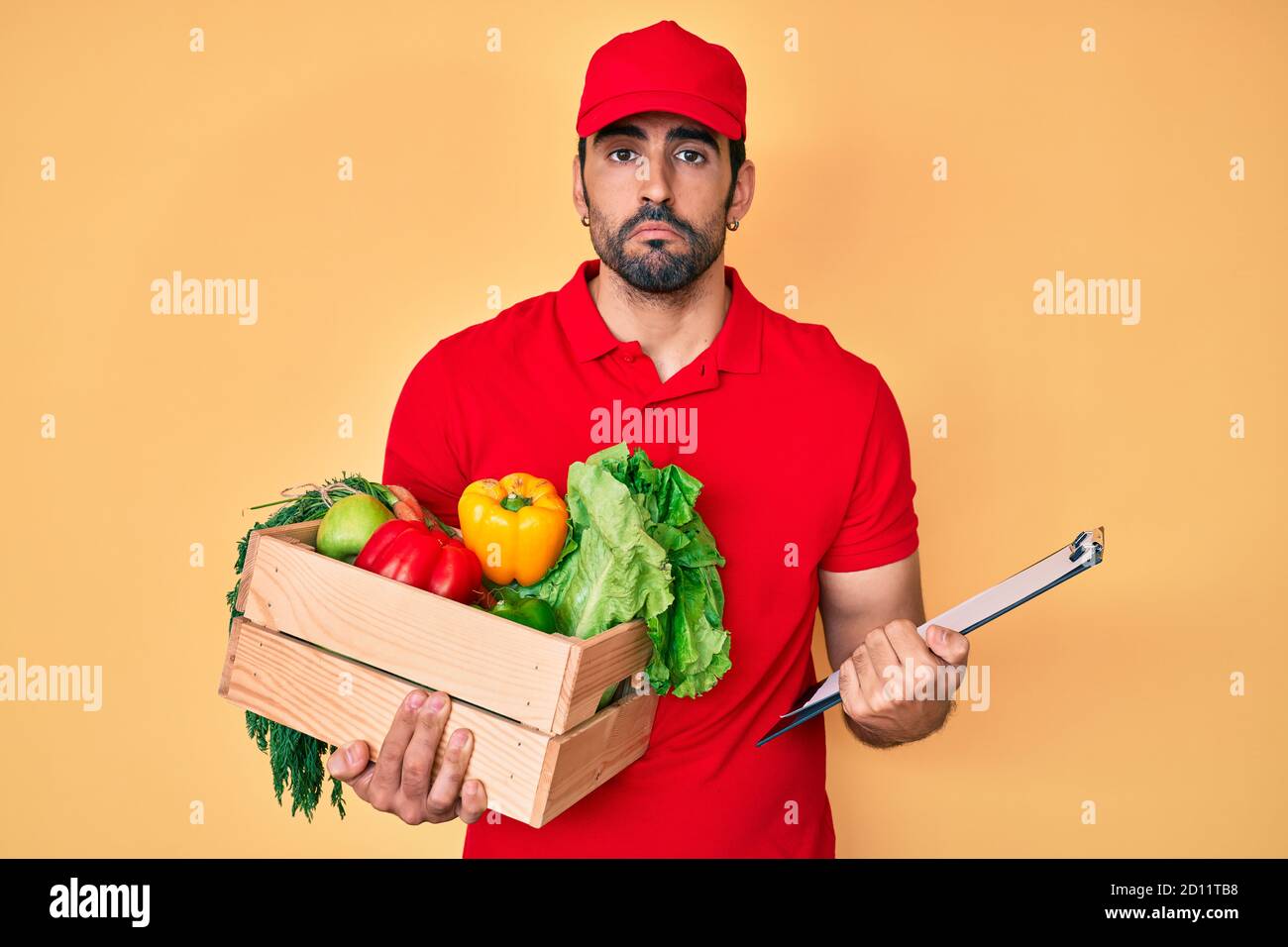 Handsome hispanic man with beard wearing uniform holding delivery food ...