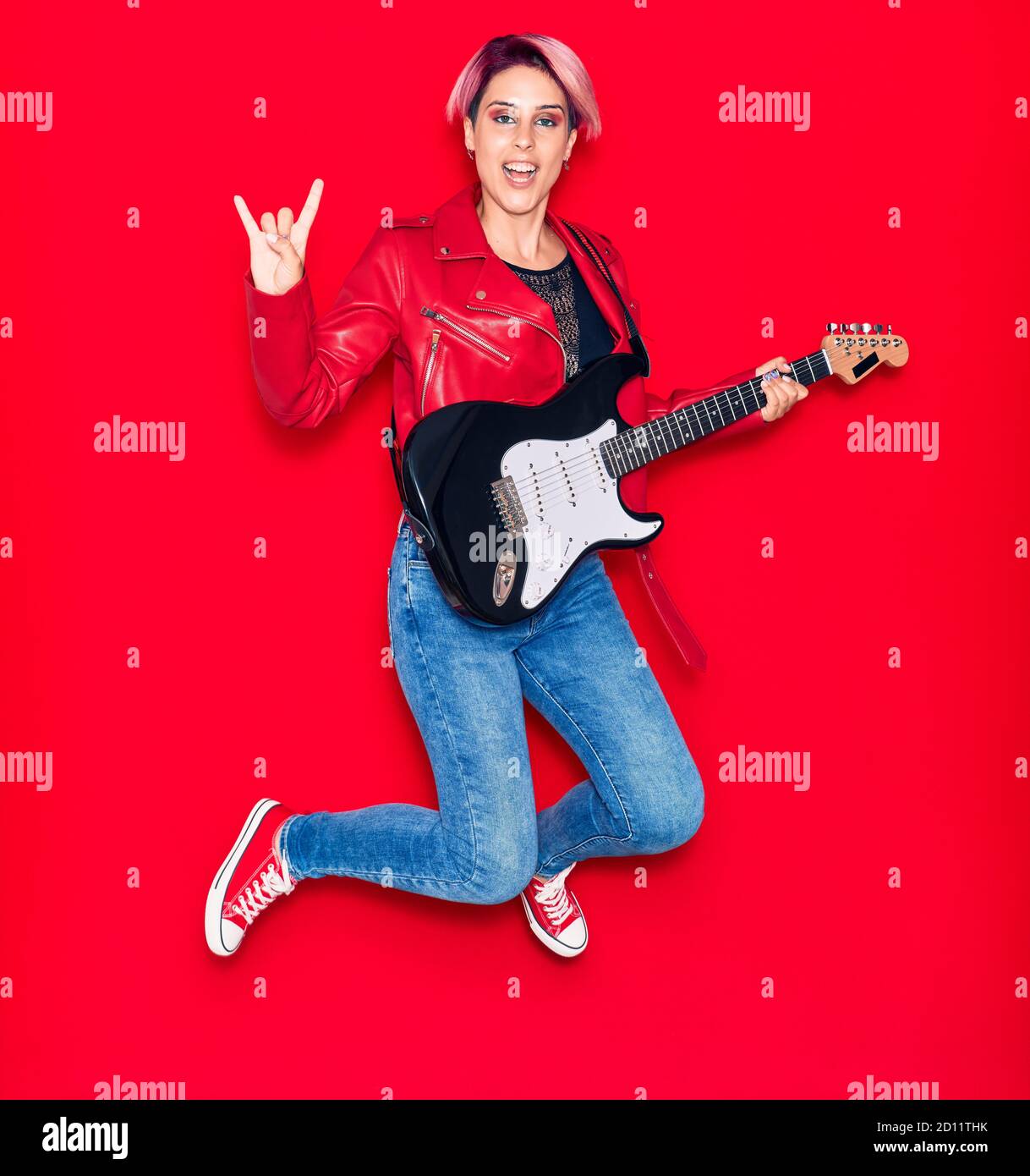 Young beautiful guitarist woman with pink short hair playing electric ...