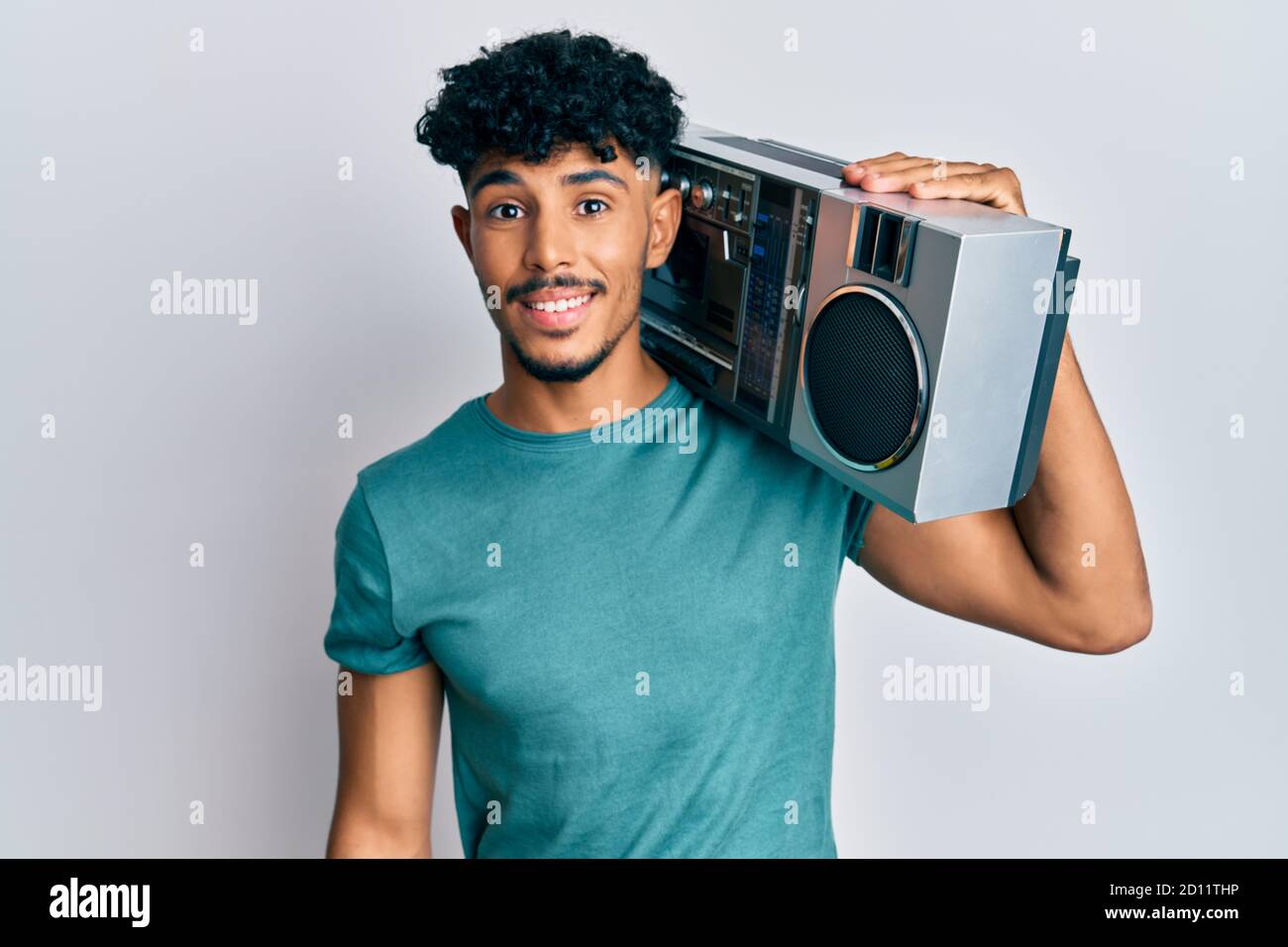 Young arab handsome man holding boombox, listening to music looking ...