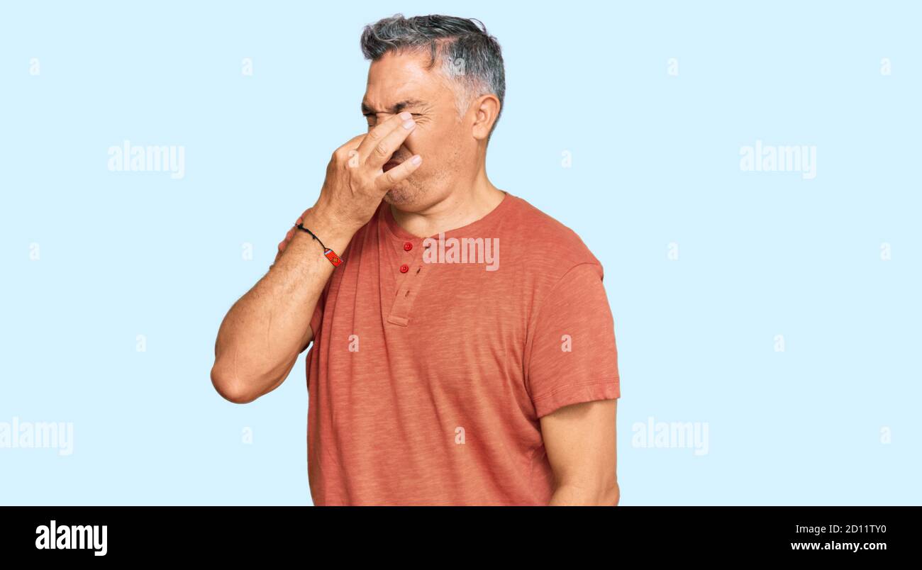 Handsome middle age man wearing casual clothes smelling something ...